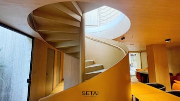 Escadaria em espiral em um interior moderno, com área de escritório visível e espaço para refeições.