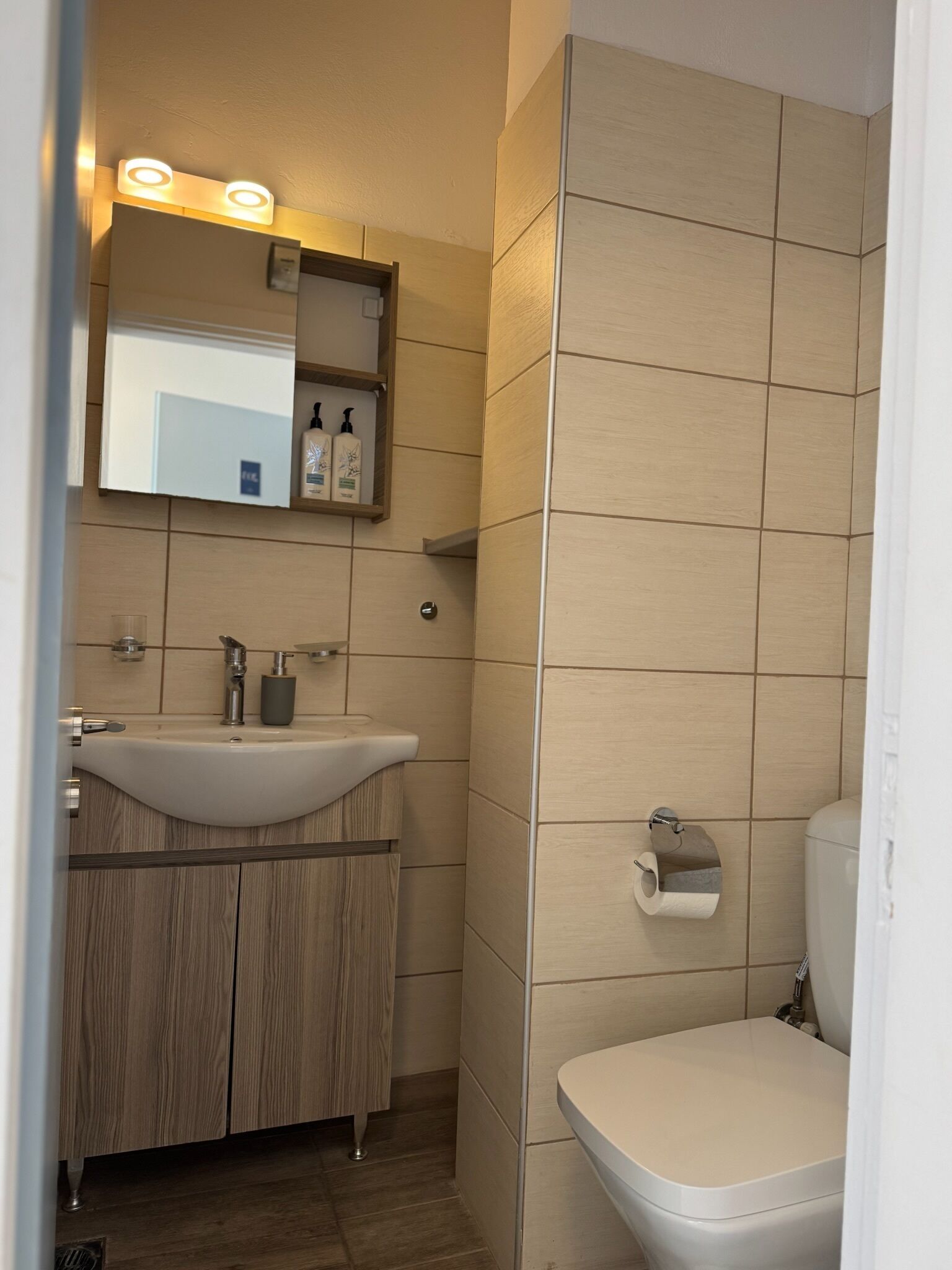 Casa de banho compacta com lavatório, espelho e sanita.