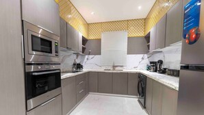 Cozinha moderna com eletrodomésticos de aço inoxidável, bancada de mármore e teto estampado.