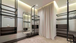 Quarto de hotel moderno com armários embutidos, um espelho grande e cores neutras.