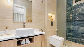 Uma casa de banho moderna com lavatório branco, espelho e sanita.