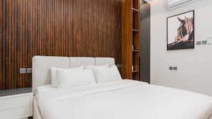 Quarto moderno com parede de ripas de madeira, cama branca e quadro com uma imagem de um cavalo.