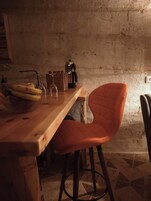Uma cozinha rústica com uma mesa de madeira, uma cadeira vermelha e uma cafeteira.
