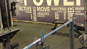 Uma academia com diversos equipamentos de exercício e uma parede motivacional com palavras como 'POWER', 'ACTIVE' e 'SUCCESS'.