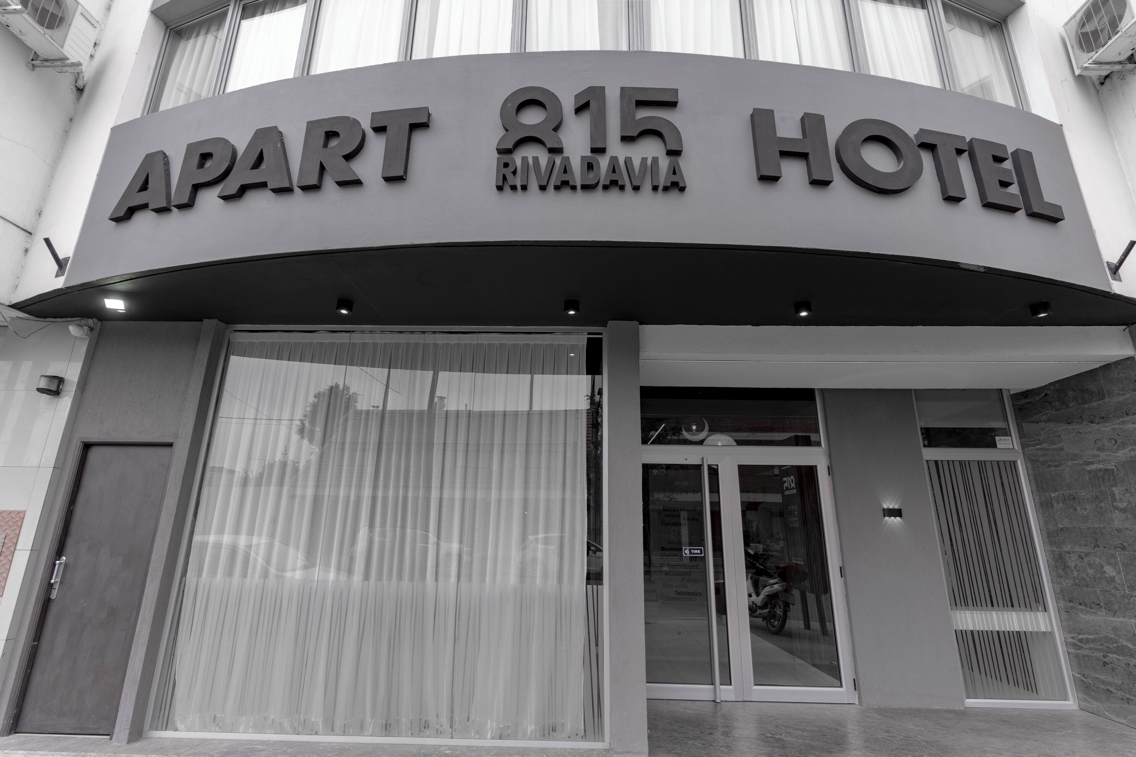 Exterior do Hotel Apt 815, com design moderno, destacando grandes portas de vidro e uma placa chamativa.