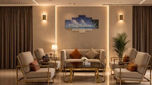 Um saguão de hotel moderno com área de estar central, uma grande obra de arte na parede e um vaso de planta.