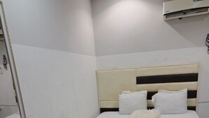 Quarto de hotel com cama, uma cadeira, um espelho e ar condicionado.