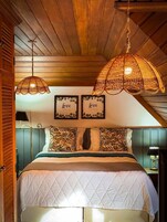 Um quarto com cama, duas luminárias fixadas na parede e duas fotografias emolduradas com a palavra 'Love'.