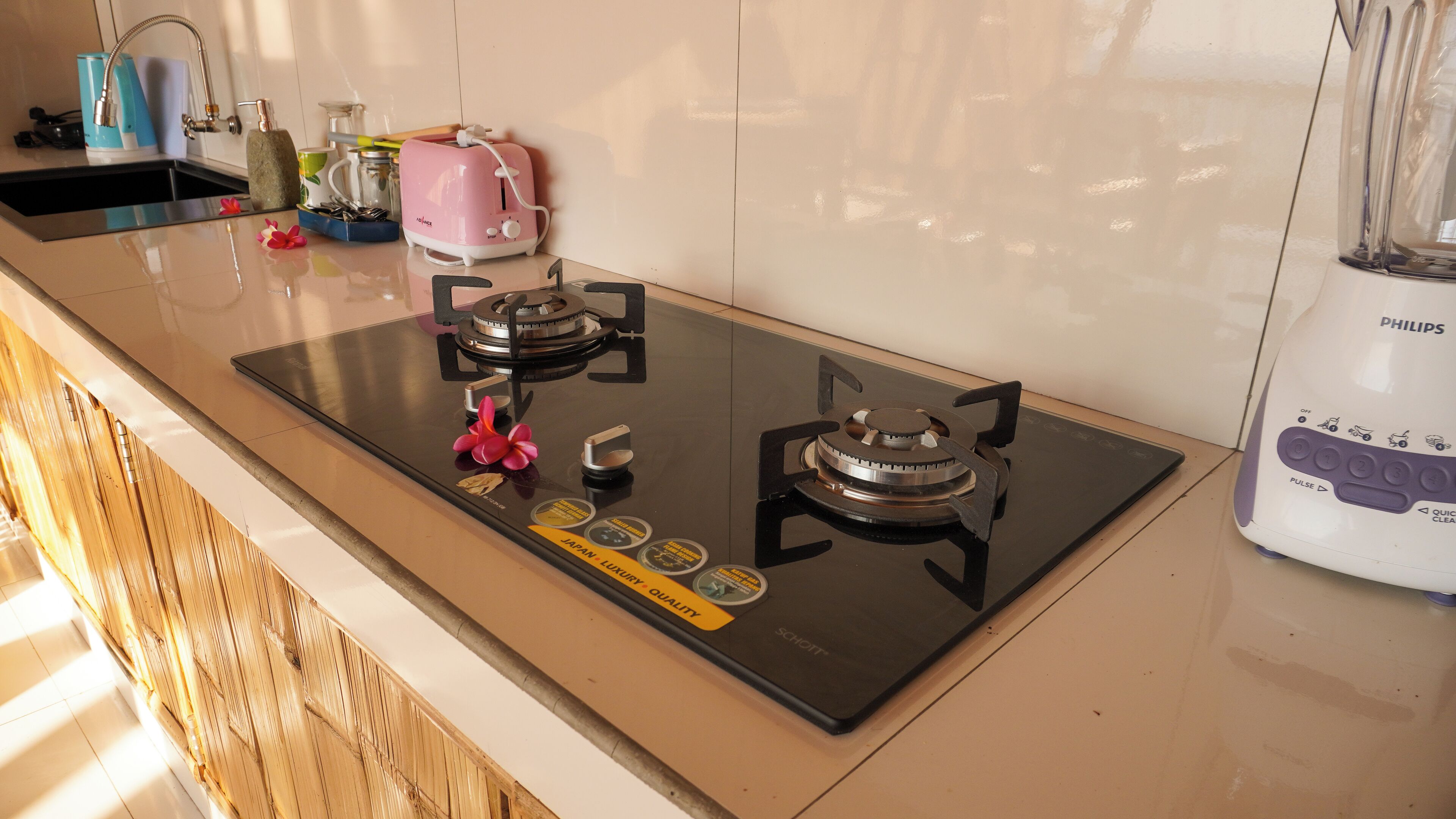 Uma cozinha com fogão preto, torradeira e liquidificador sobre o balcão.