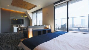 Quarto de hotel moderno com uma cama grande, uma escrivaninha com televisão de tela plana, micro-ondas e vista para a cidade através de grandes janelas.