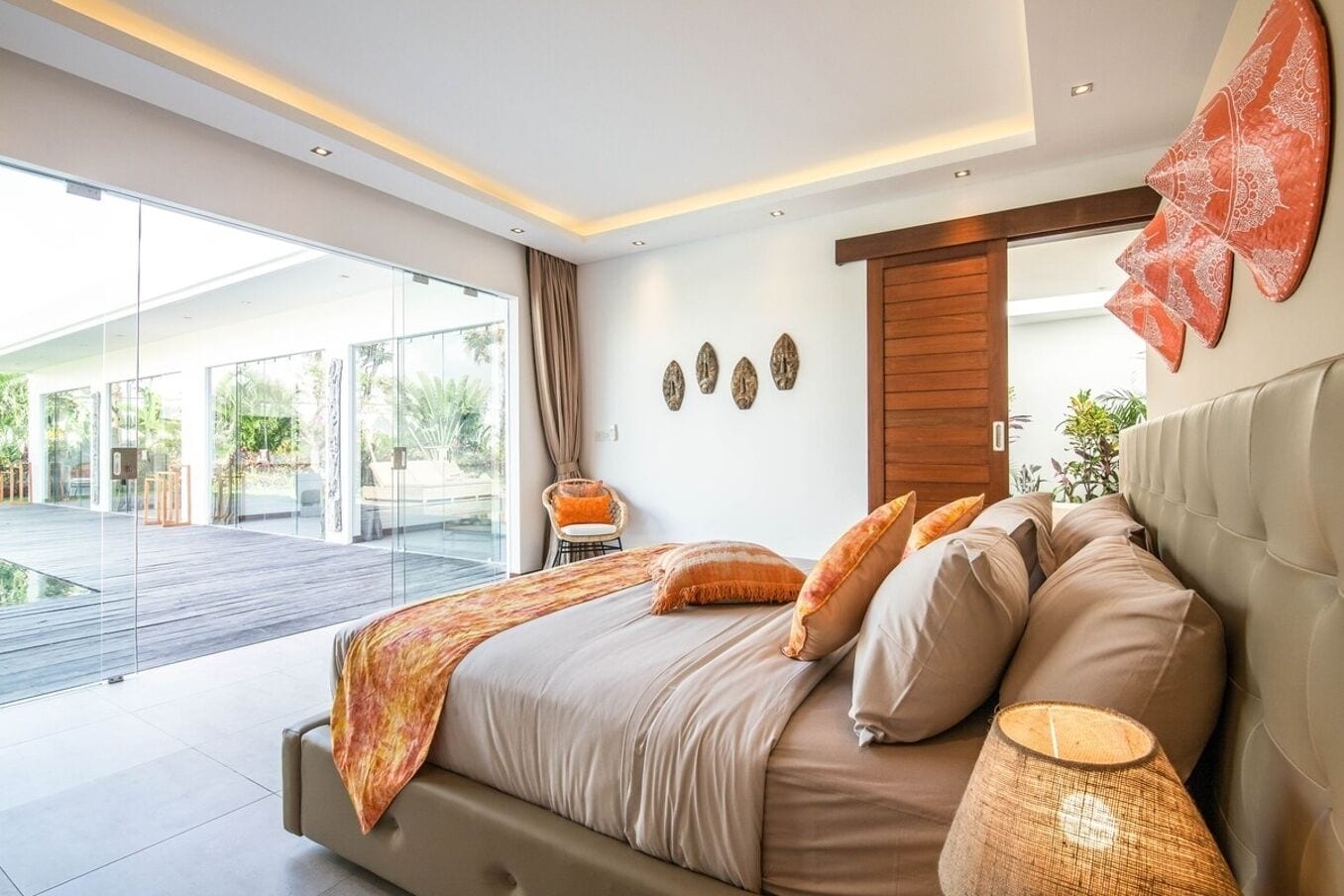 Quarto moderno com uma cama grande, uma porta de vidro que dá para uma área externa e uma porta de madeira.