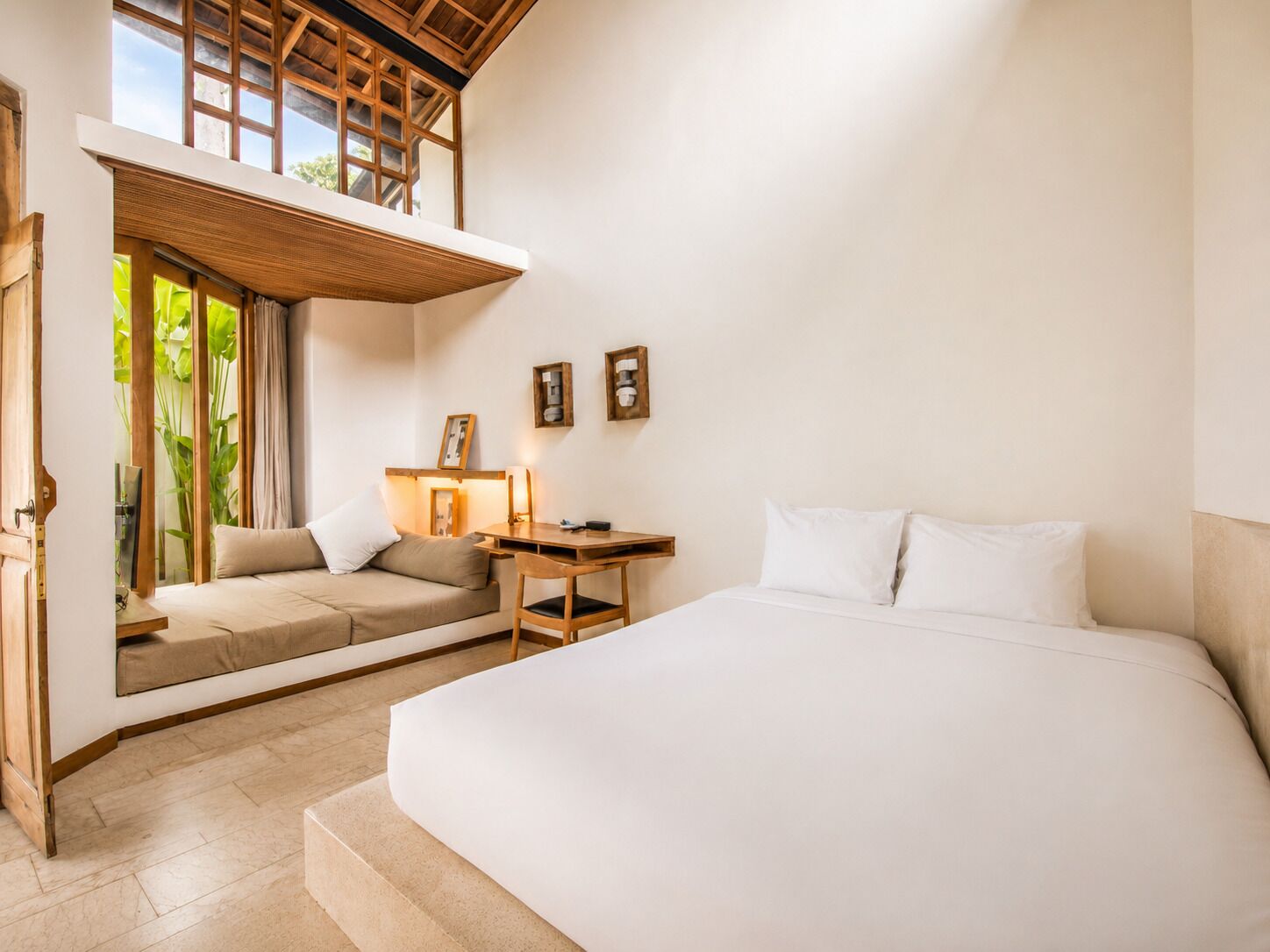 Quarto com cama, escrivaninha, cadeira e janela com vista para o verde.