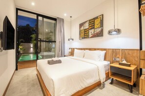 Quarto de hotel moderno com uma cama grande, cabeceira de madeira, mesa de cabeceira, televisão de tela plana e vista para uma piscina ao ar livre.