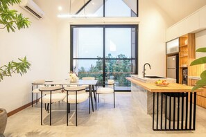 Cozinha moderna com uma janela grande, área de refeições com cadeiras e uma pequena ilha com pia.