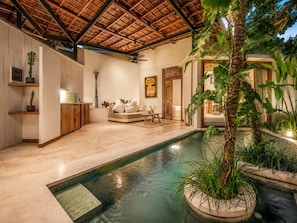 Interior moderno com piscina, teto de madeira e plantas.