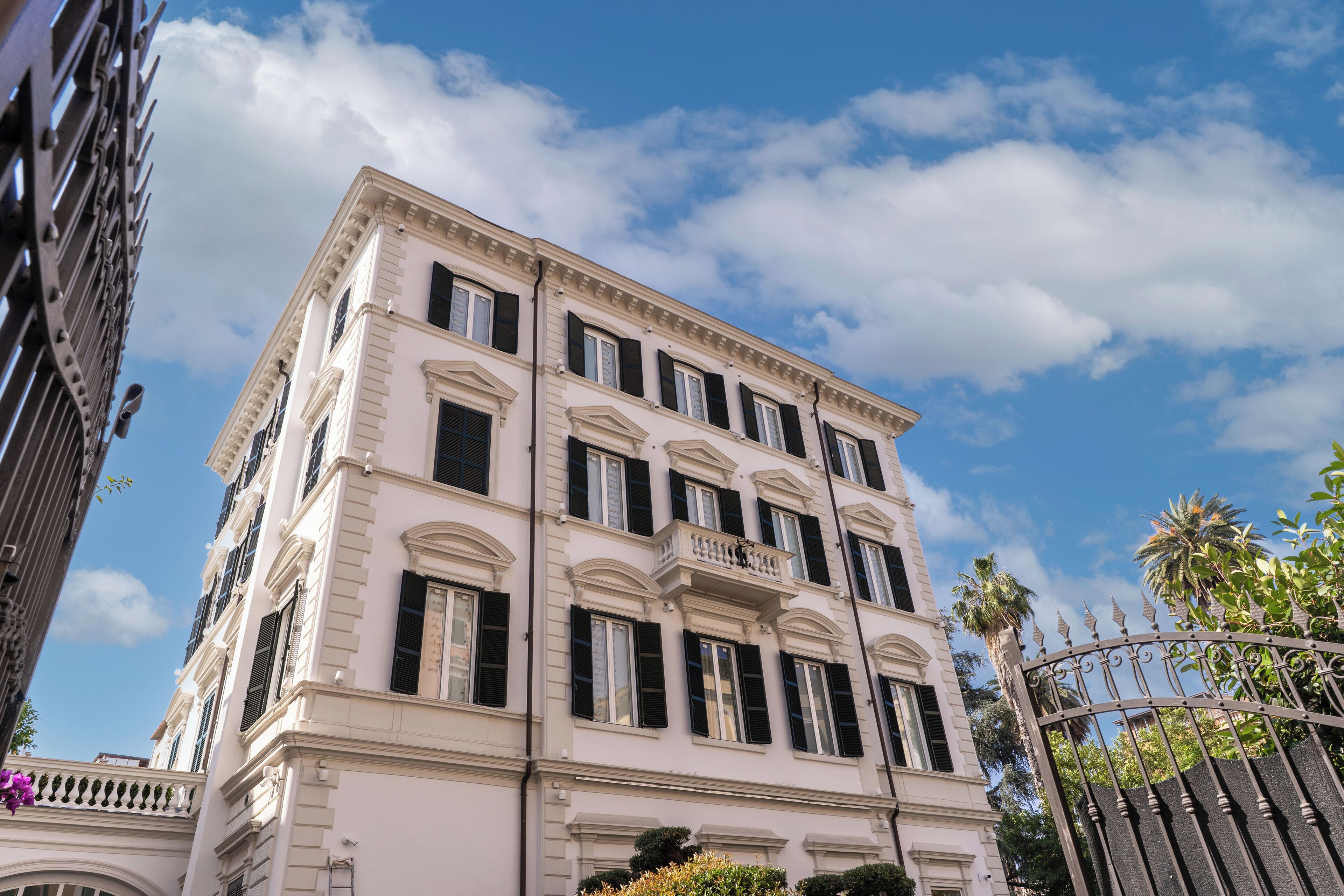 Um edifício de vários andares com estilo arquitetônico clássico, apresentando janelas simétricas e uma varanda central.