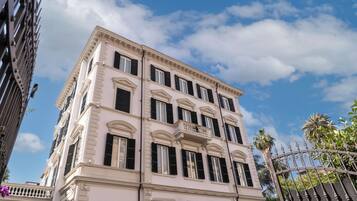 Um edifício de vários andares com estilo arquitetônico clássico, apresentando janelas simétricas e uma varanda central.