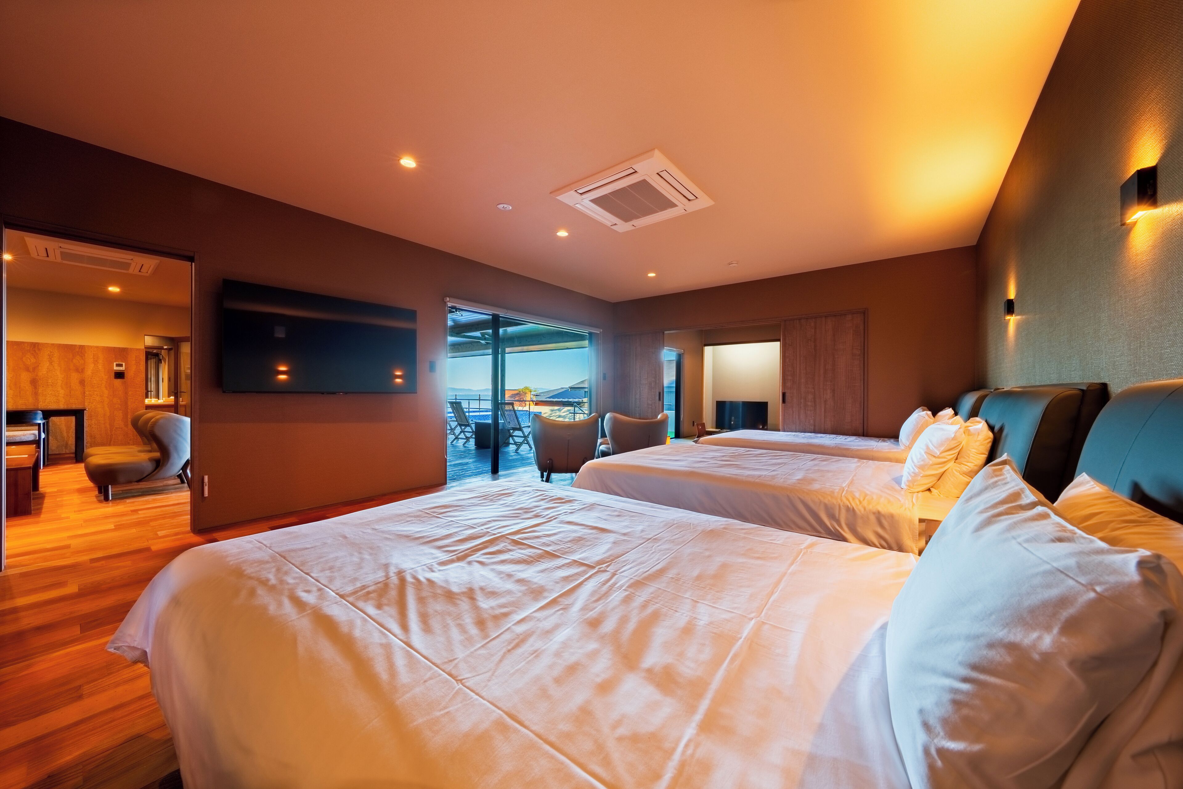 Quarto de hotel com duas camas, televisão e vista para o exterior.