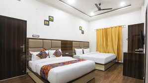 Quarto de hotel com duas camas, um ventilador de teto e uma janela grande com cortinas.