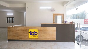 Bancada de recepção de hotel com balcão de madeira e uma placa que diz 'fab hotels'.