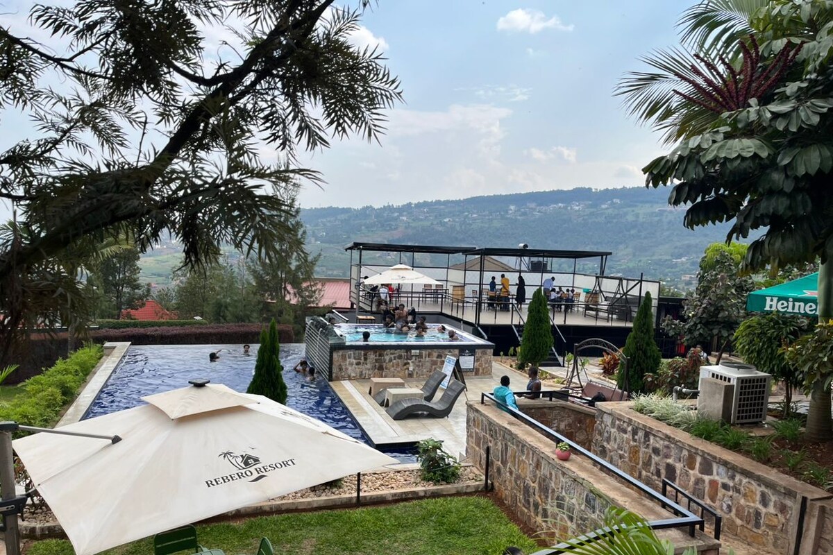 Área de piscina no terraço com espreguiçadeiras, bar e vista para a paisagem urbana.