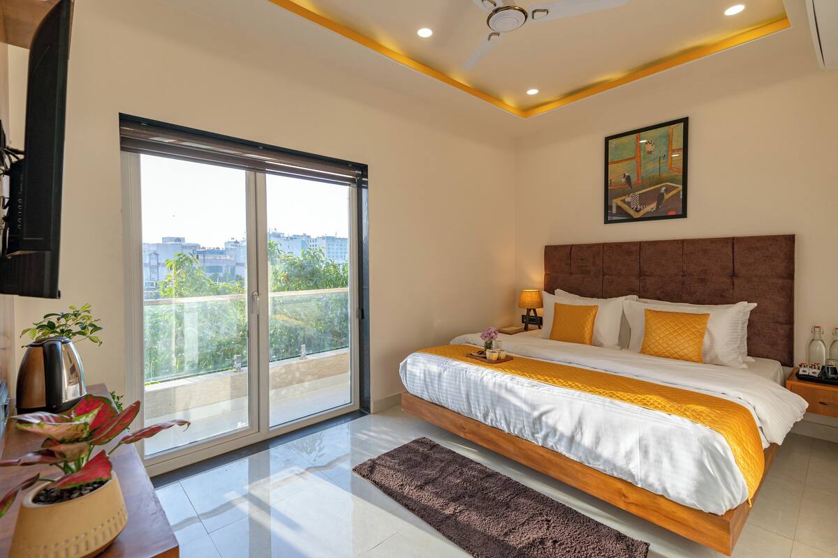 Quarto moderno com cama grande, televisão, varanda e vista para a cidade.