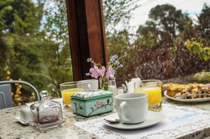 Uma mesa de café da manhã com um copo de suco de laranja, uma xícara, uma pequena caixa decorativa e um prato de comida.