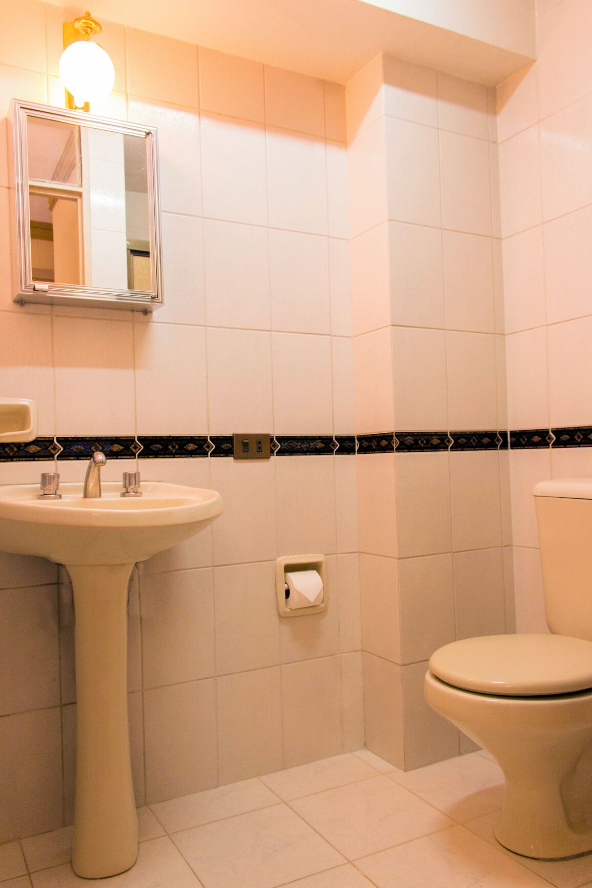 Um banheiro com pia de pedestal, vaso sanitário e espelho.