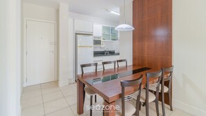 Uma cozinha moderna com armários brancos, uma mesa de jantar de madeira e quatro cadeiras.