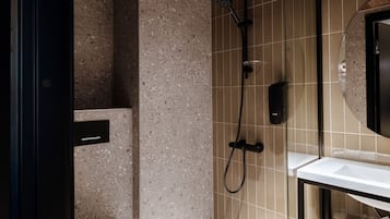 Uma casa de banho moderna com chuveiro, pia e espelho.