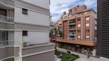 Um edifício residencial com vários andares, varandas, um terraço no telhado e um espaço comercial no nível da rua.