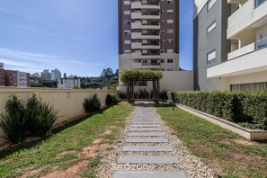 Um caminho leva a um edifício de design moderno, cercado por vegetação e céu claro.