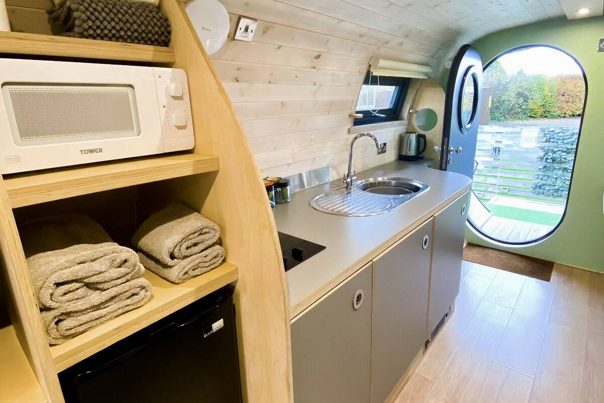 Cozinha compacta com micro-ondas, pia e janela com vista para o exterior.