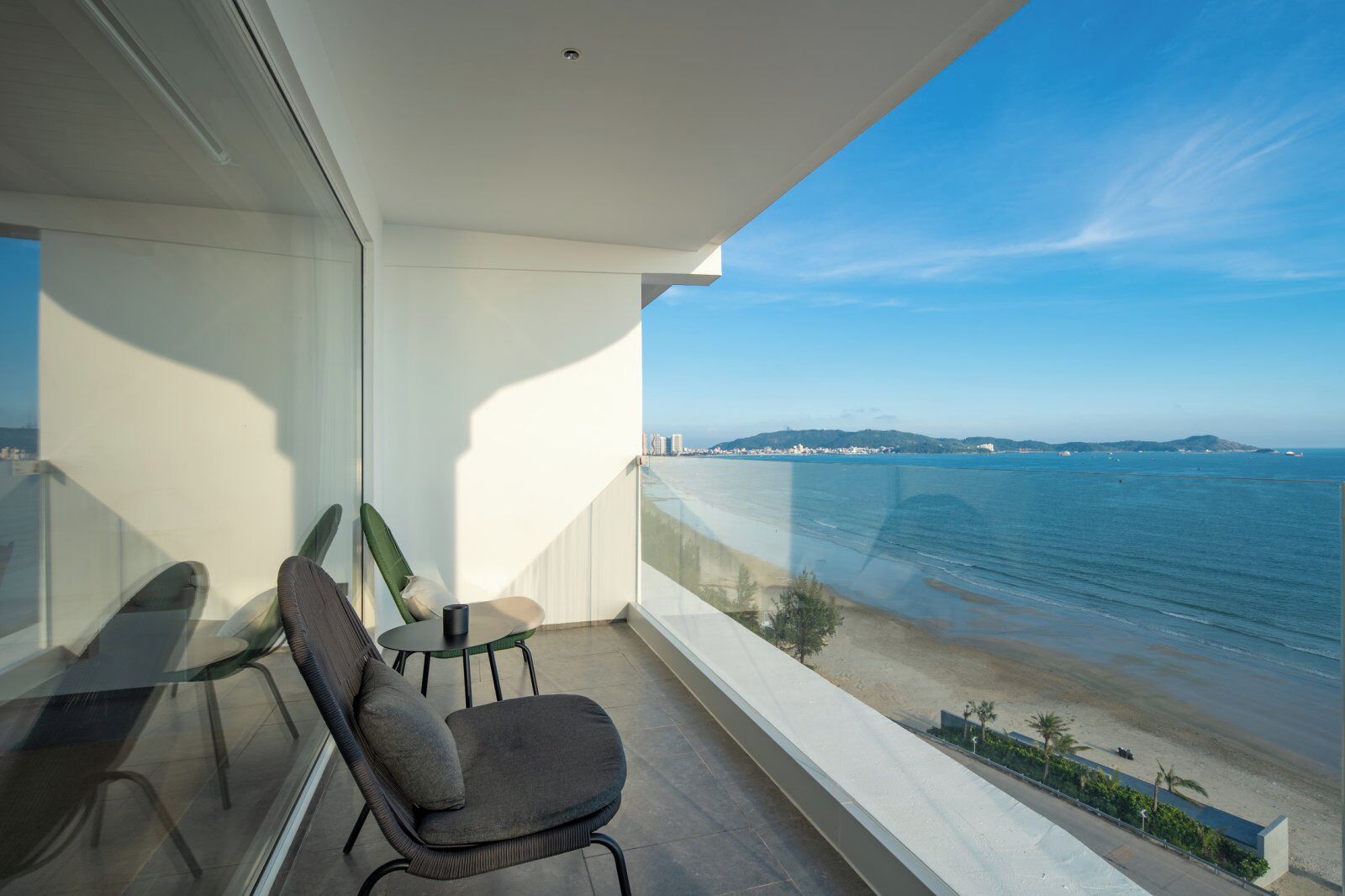 Uma varanda com vista para o mar, uma cadeira e uma mesa pequena.