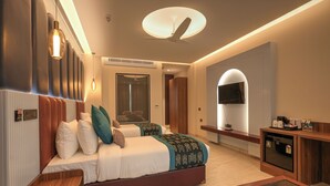Quarto de hotel moderno com uma cama grande, televisão, escrivaninha e minibar.