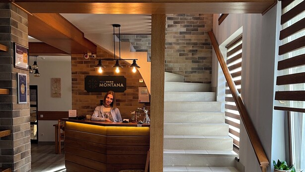 Interior moderno com balcão de recepção em madeira, escada com corrimão de madeira e uma placa indicando Montana.