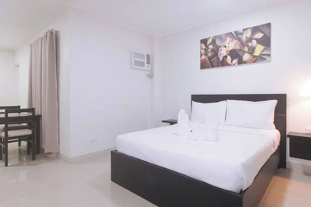 Quarto de hotel com uma cama, uma escrivaninha e uma cadeira.