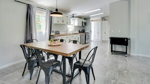 Cozinha moderna com armários brancos, mesa de jantar de madeira e cadeiras pretas.
