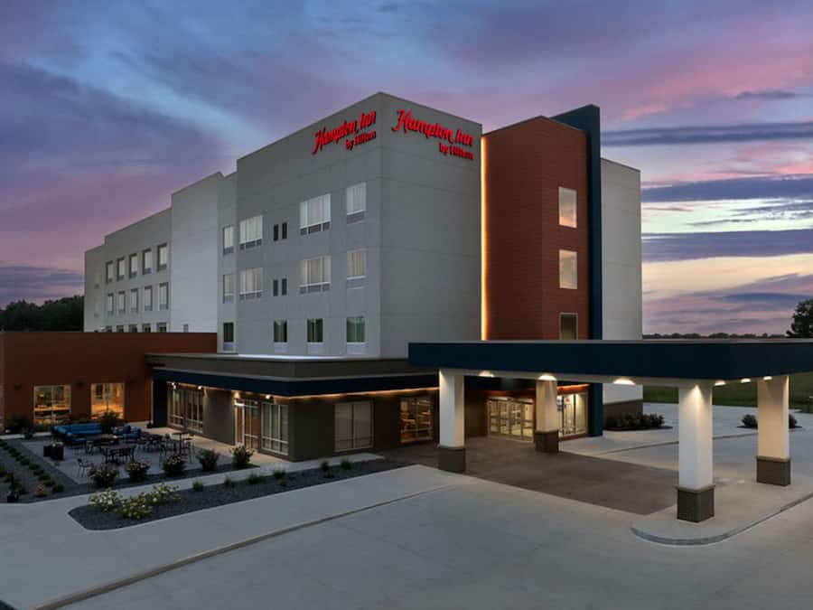 Um hotel Hampton Inn com design moderno, apresentando um telhado plano e uma sinalização chamativa.