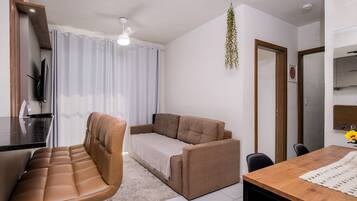 Uma sala de estar moderna com sofá, poltrona, mesa de madeira e ventilador de teto.