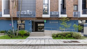 Um edifício moderno com o número 258, destacando uma entrada imponente, uma varanda com grades e uma área de jardim bem cuidada.