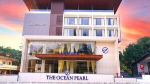 Um hotel moderno com uma placa que diz "THE OCEAN PEARL" e "KASHIPALACE" em cima.
