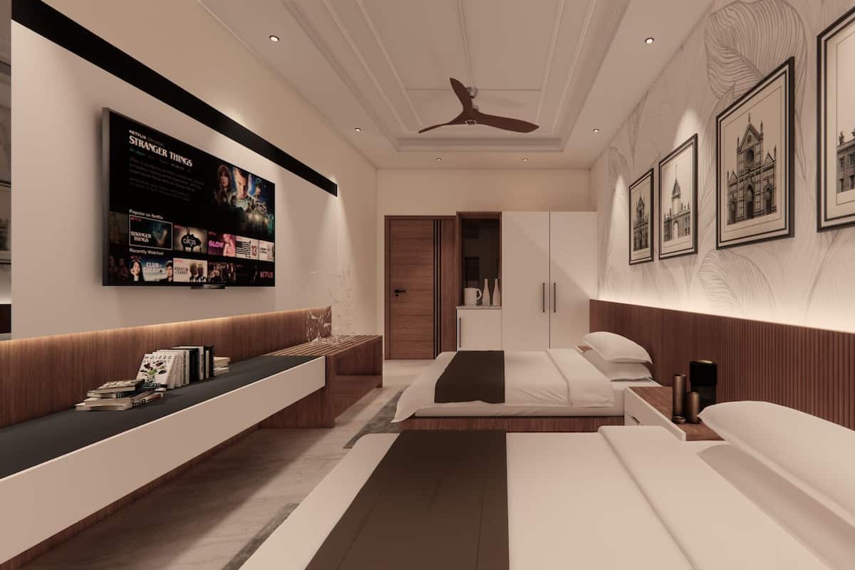 Quarto de hotel moderno com cama, área de estar com mesinha de café, TV fixada na parede exibindo um programa da Netflix e quadros nas paredes.
