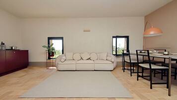 Sala de estar com sofá, mesa de jantar, cadeiras e um vaso de planta.