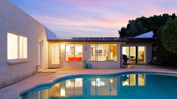 Uma casa moderna com piscina, janelas amplas e interior bem iluminado.