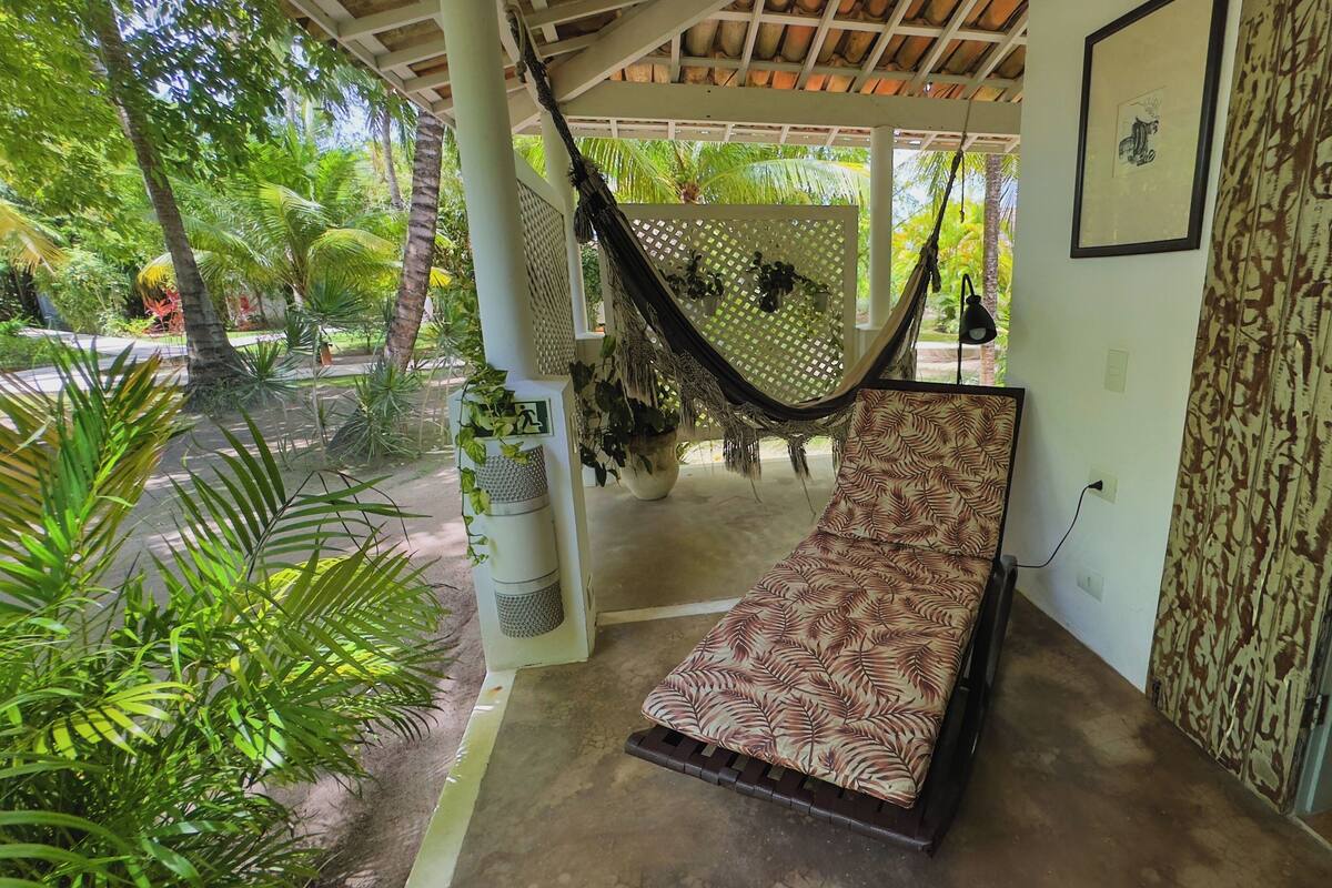 Uma rede em um espaço externo coberto com vista para plantas tropicais.