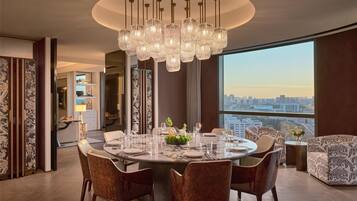 Uma sala de jantar moderna com uma mesa redonda, várias cadeiras e um candelabro.