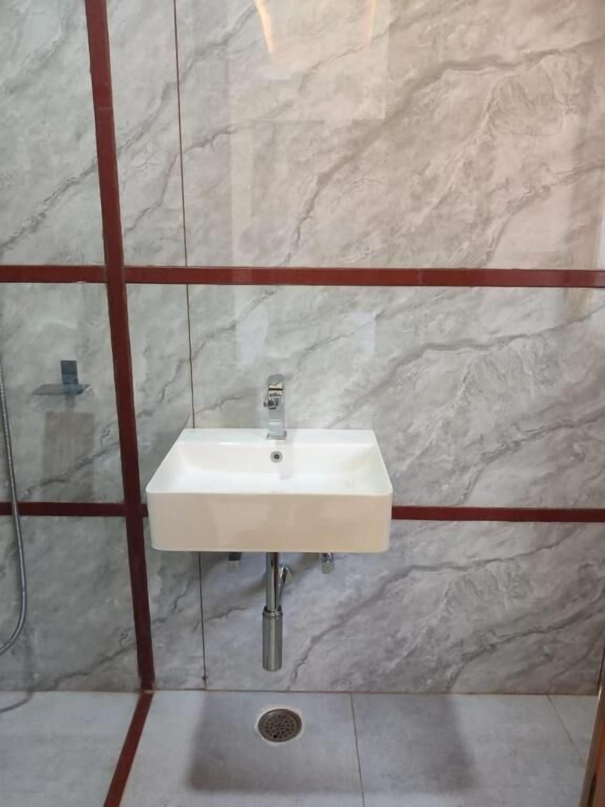 Casa de banho com lavatório branco, espelho e zona de duche.