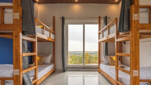 Quarto com quatro beliches, numerados de 01 a 04, e uma grande porta de correr que dá para uma varanda com vista.