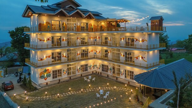 Um hotel com vários andares, varandas, área externa para sentar e um pátio bem iluminado.